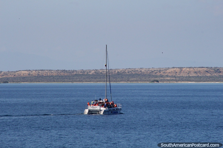 Catamaran with many people aboard cruises the waters off Cubagua Island ...